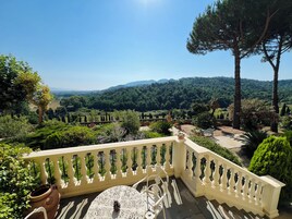 Uma varanda com vista para um jardim exuberante e montanhas ao longe.