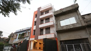 Um edifício residencial com vários andares, entrada com portão, varandas e uma loja visível no andar térreo.