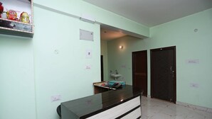 Uma área de recepção com balcão, interfone fixado na parede e porta para outro ambiente.