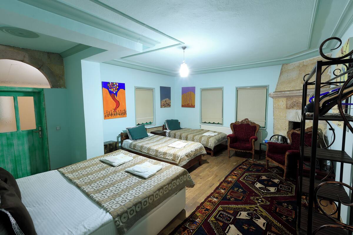 Quarto com duas camas, uma poltrona vermelha e um tapete estampado.