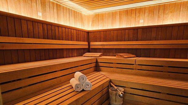 Uma sauna com bancos e toalhas de madeira, além de um balde.