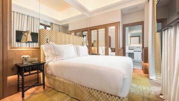 Quarto de hotel com uma cama grande, uma mesa de cabeceira, um espelho e vista para o banheiro.