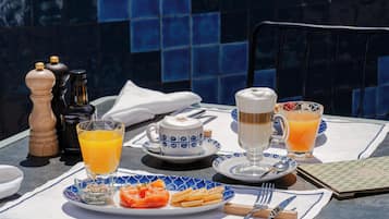 Uma mesa de café da manhã com um prato de comida, um copo de suco de laranja e uma xícara de café.