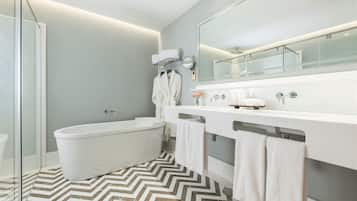 Uma casa de banho moderna com uma banheira independente, um espelho grande e um lavatório branco.