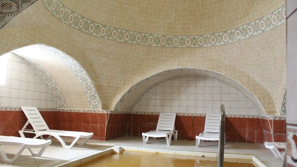 Área de piscina com cadeiras de descanso brancas e uma escada.