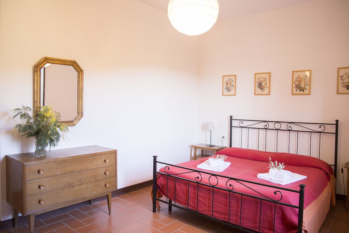 Um quarto com cama, penteadeira, espelho e obras de arte na parede.