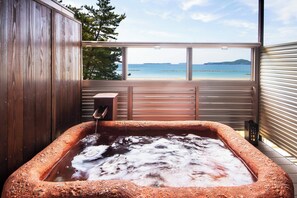 Uma banheira de hidromassagem com vista para a praia e montanhas.