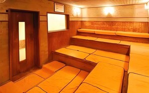 Quarto com paredes de madeira e uma porta, apresentando um conjunto de degraus que levam a um espaço de estar com bancos acolchoados.
