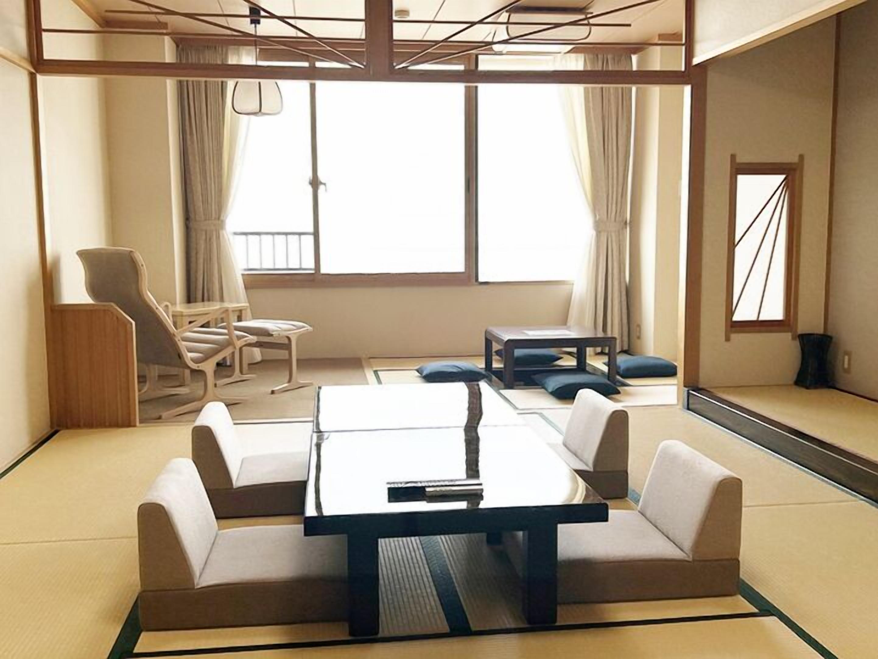 Quarto com piso de tatame, mesa baixa com almofadas, sofá e cadeira.