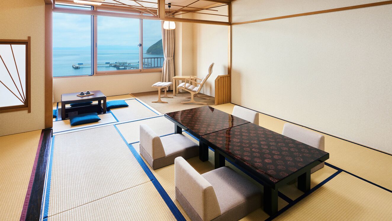 Um quarto com tatames, uma mesa baixa e cadeiras, vista para o mar e uma janela grande.