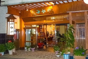 Uma loja tradicional japonesa com letreiros de madeira e entrada coberta por telhas.