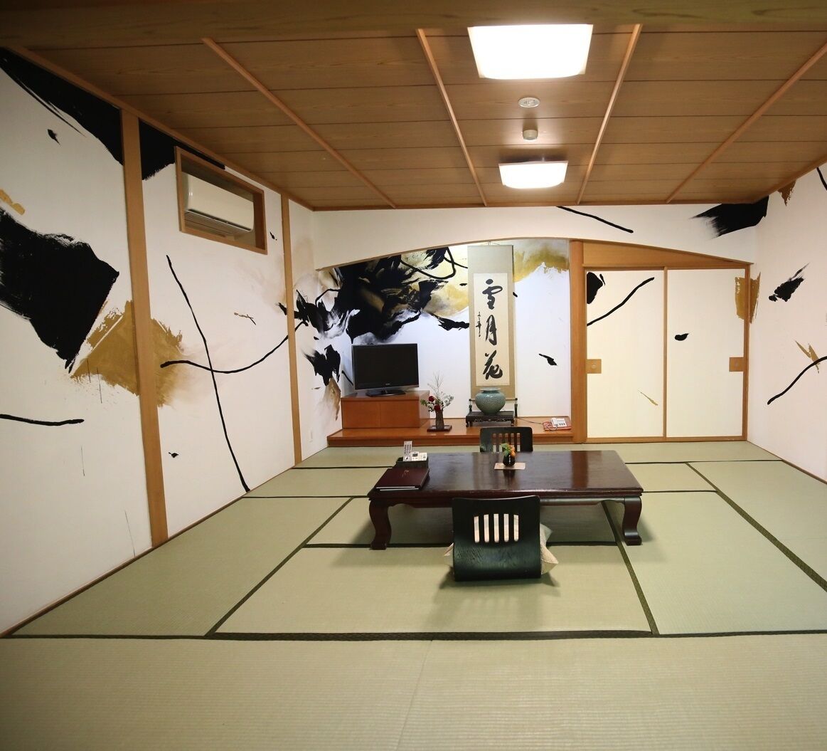Um quarto tradicional japonês com tatames, uma mesa baixa, uma televisão e um futum.