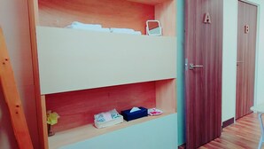 Uma cama beliche com uma prateleira inferior que contém uma cesta, um estojo de lenços e um pequeno objeto.