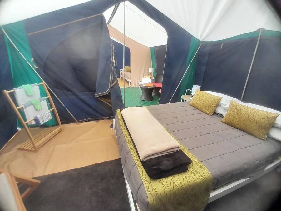 Um quarto com tenda, uma cama, uma mesinha e uma cadeira.
