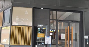 Entrada de hotel com design moderno, balcão de recepção e máquina de pagamento à vista.