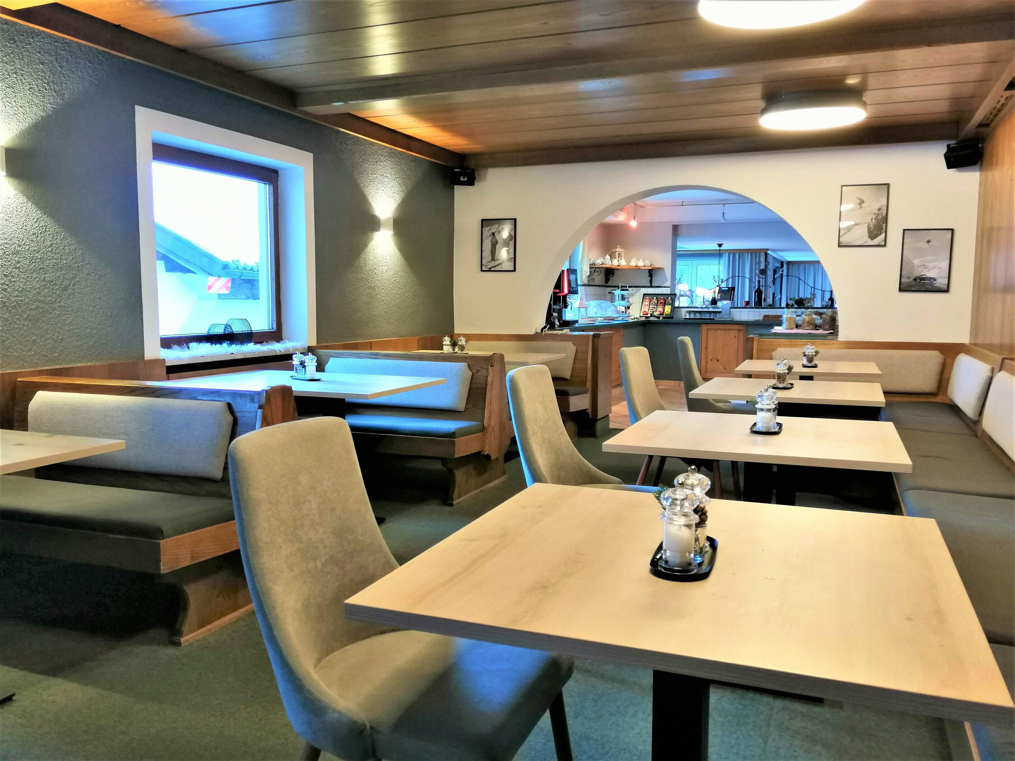 Um restaurante com cabines e mesas, cozinha ao fundo e uma tela de projeção na parede.