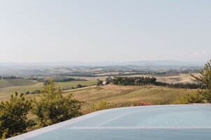 Uma vista panorâmica de uma paisagem com colinas ondulantes e uma cordilheira distante.