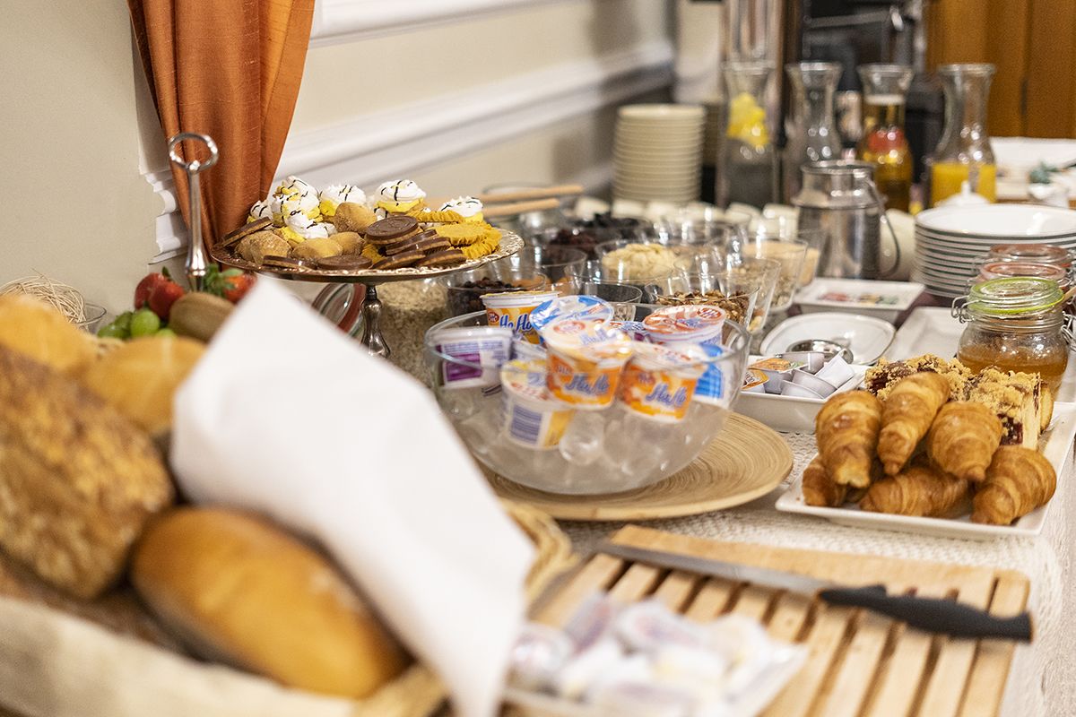 Um buffet de café da manhã com diversos pães, bolos e produtos lácteos.