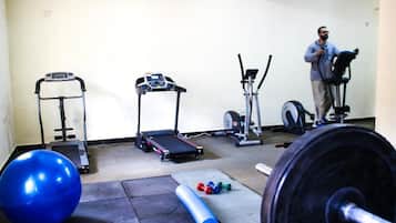 Uma academia em casa com esteira, elíptico, bicicleta ergométrica e banco de musculação.
