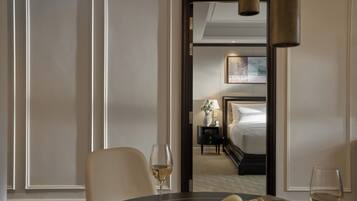 Quarto de hotel com área de refeições, cama e mesa de cabeceira com abajur.