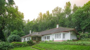 Uma casa branca com telhado vermelho, rodeada por muita vegetação e árvores.