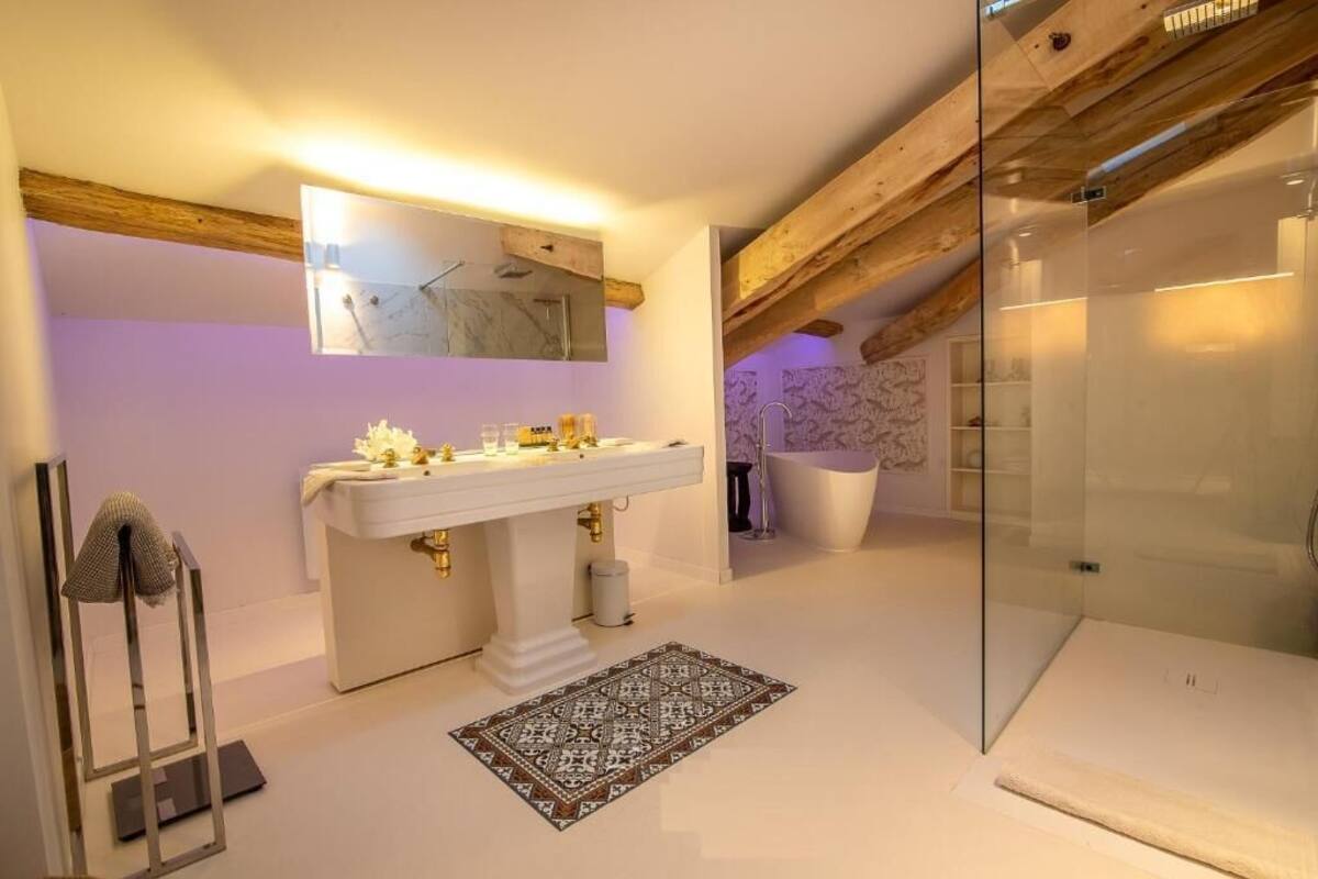 Uma casa de banho moderna com uma toucador branco, um espelho grande e uma cabine de duche com portas de vidro.