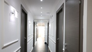 Corredor com portas em ambos os lados, iluminação embutida e piso cerâmico.
