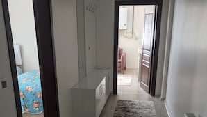 Um corredor com tapete estampado, um guarda-roupa branco e uma cama com colcha florida.