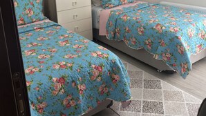 Quarto com duas camas, cada uma com roupa de cama florida, um aparador branco e um tapete estampado.