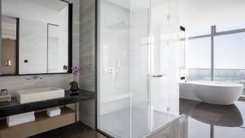 Uma casa de banho moderna com um espelho grande, uma sanita branca, uma banheira independente e um chuveiro com parede de vidro.