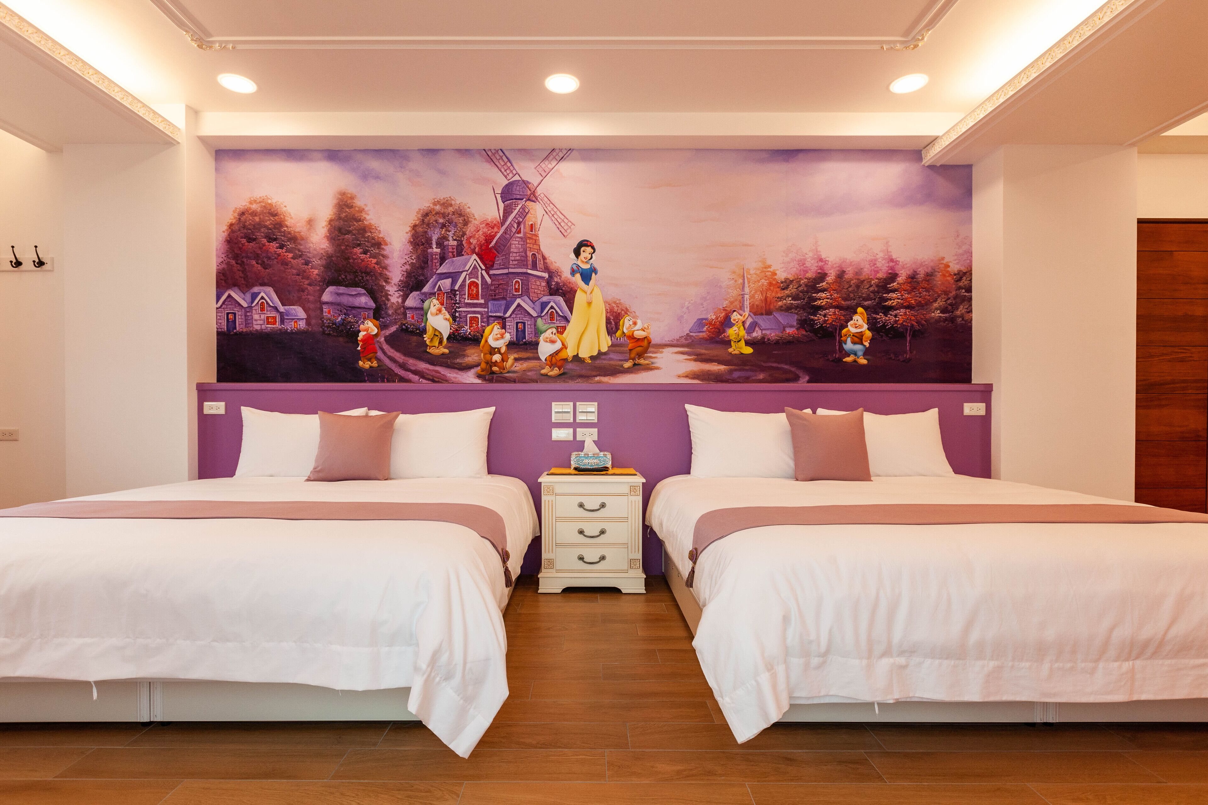 Quarto de hotel com duas camas, um mural com personagens da Disney e piso de madeira.