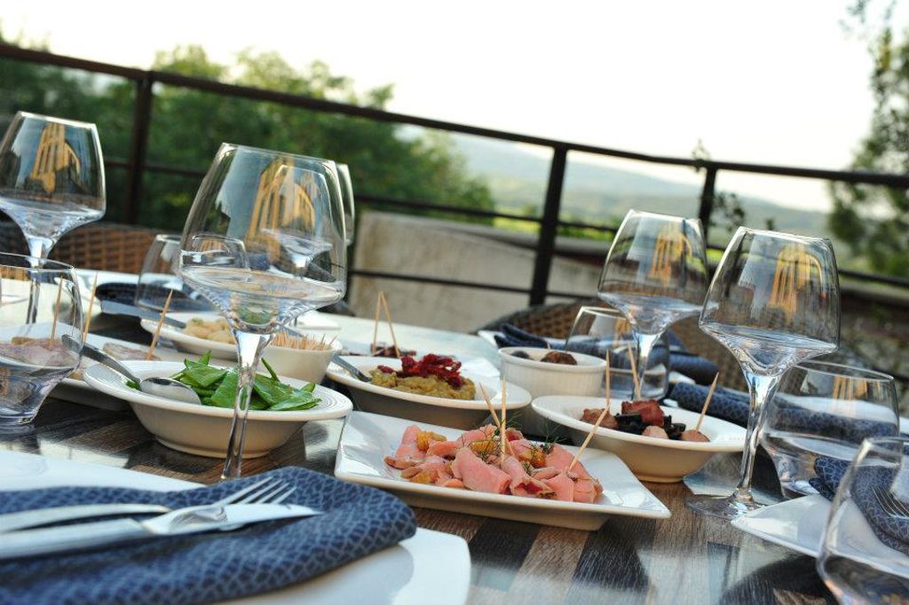 Mesa posta para refeição com diversos pratos e copos de vinho.