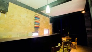 Uma área de bar com parede de pedra, cadeiras de madeira e um balcão.