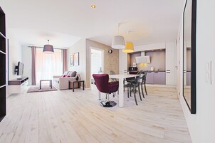 Uma sala de estar moderna com área de refeições, cozinha e uma grande janela com cortinas.