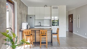 Cozinha moderna com ilha central, armários brancos e parede de tijolos.