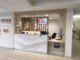 Uma receção de hotel com design moderno, uma tela digital e uma placa com o nome do hotel.