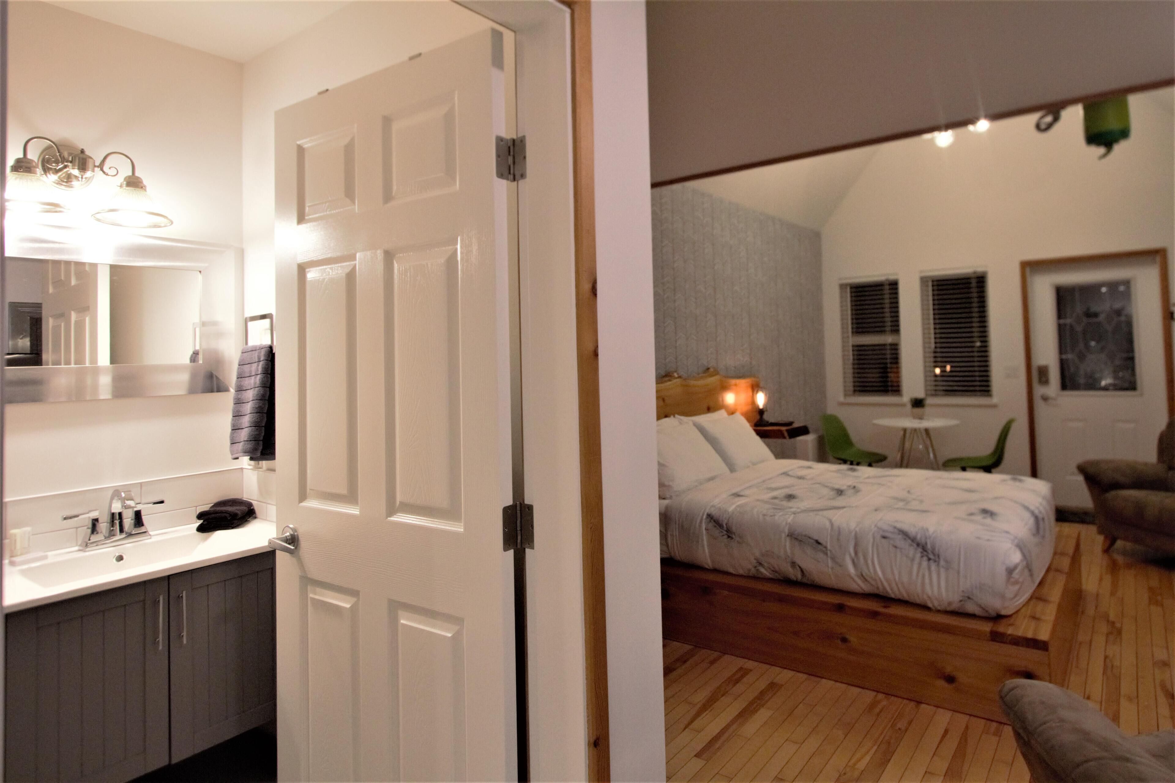 Quarto com cama de madeira, mesa de cabeceira e uma cadeira.