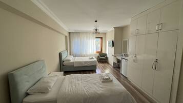 Quarto de hotel com duas camas, uma escrivaninha, um guarda-roupa e uma televisão.