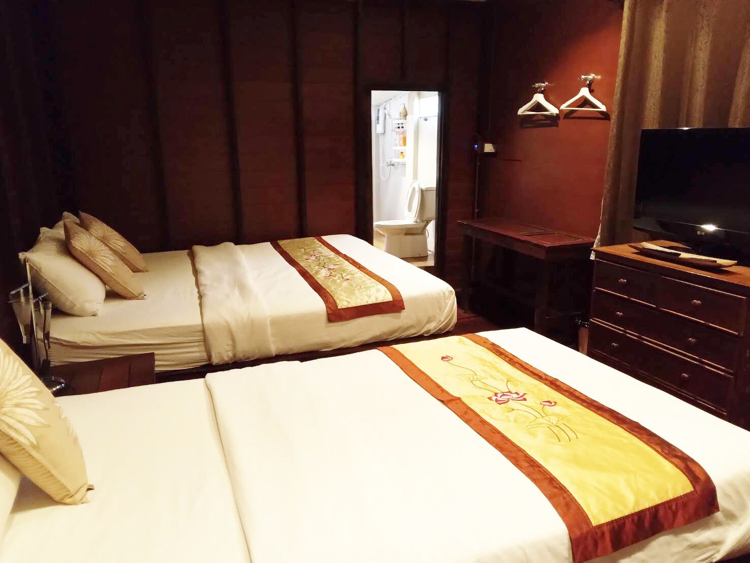 Quarto de hotel com duas camas, televisão, cômoda e espelho.