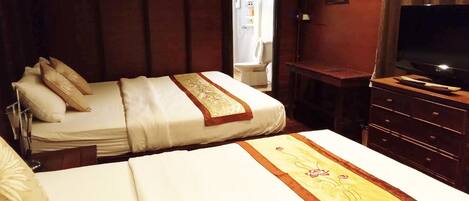 Quarto de hotel com duas camas, televisão, cômoda e espelho.