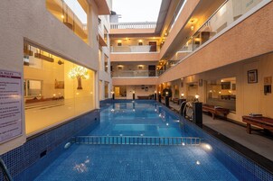 Piscina coberta com vários níveis, piso de azulejos e barreira de vidro.