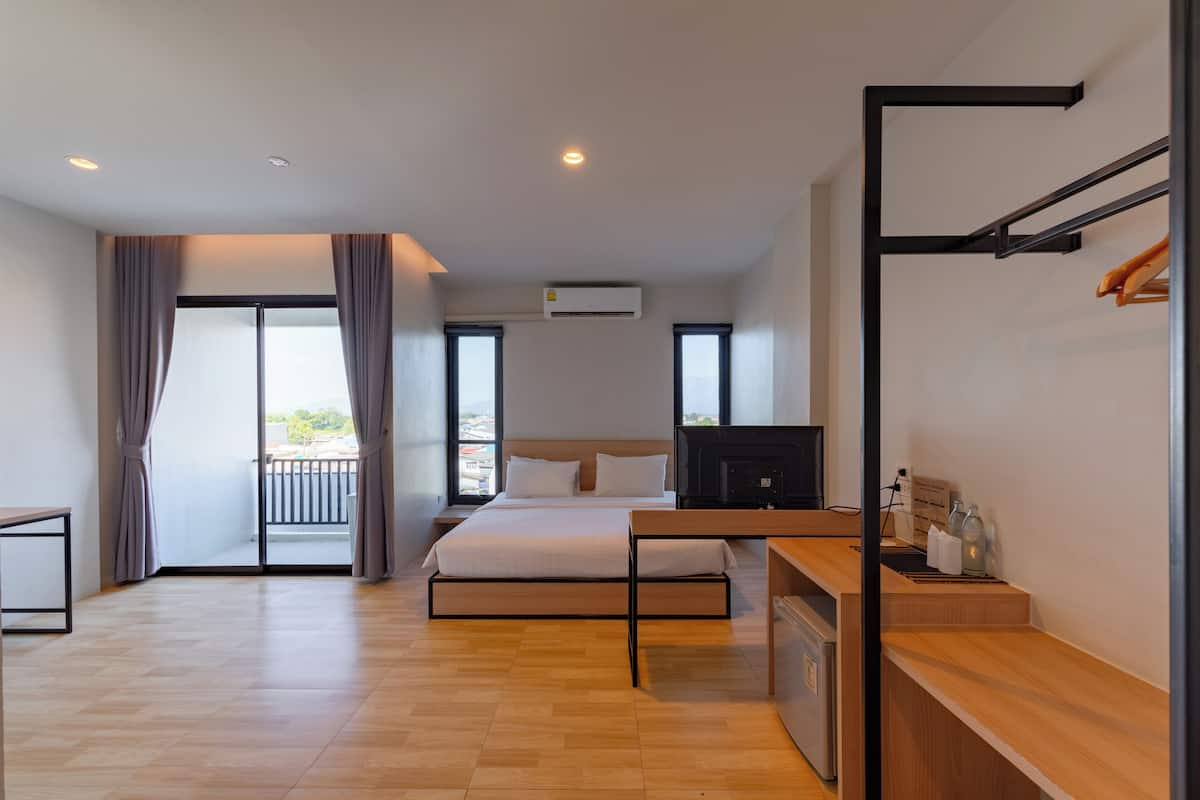 Quarto de hotel moderno com cama, escrivaninha e varanda.