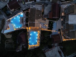 Vista aérea de uma propriedade com duas piscinas, um espaço de estar coberto e uma variedade de edifícios residenciais.