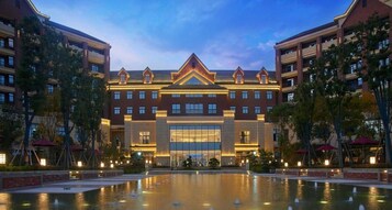 Um hotel com vários andares, um pátio central e uma piscina refletora.