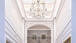 Um hall imponente com um lustre, sofás vermelhos e piso de mármore.