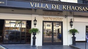 Exterior da Villa De Khaosan, com uma placa, portas de entrada e duas plantas em vasos.