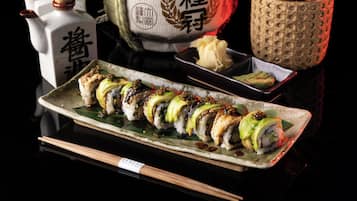 Uma seleção de sushi em um prato de cerâmica, com hashis ao lado.