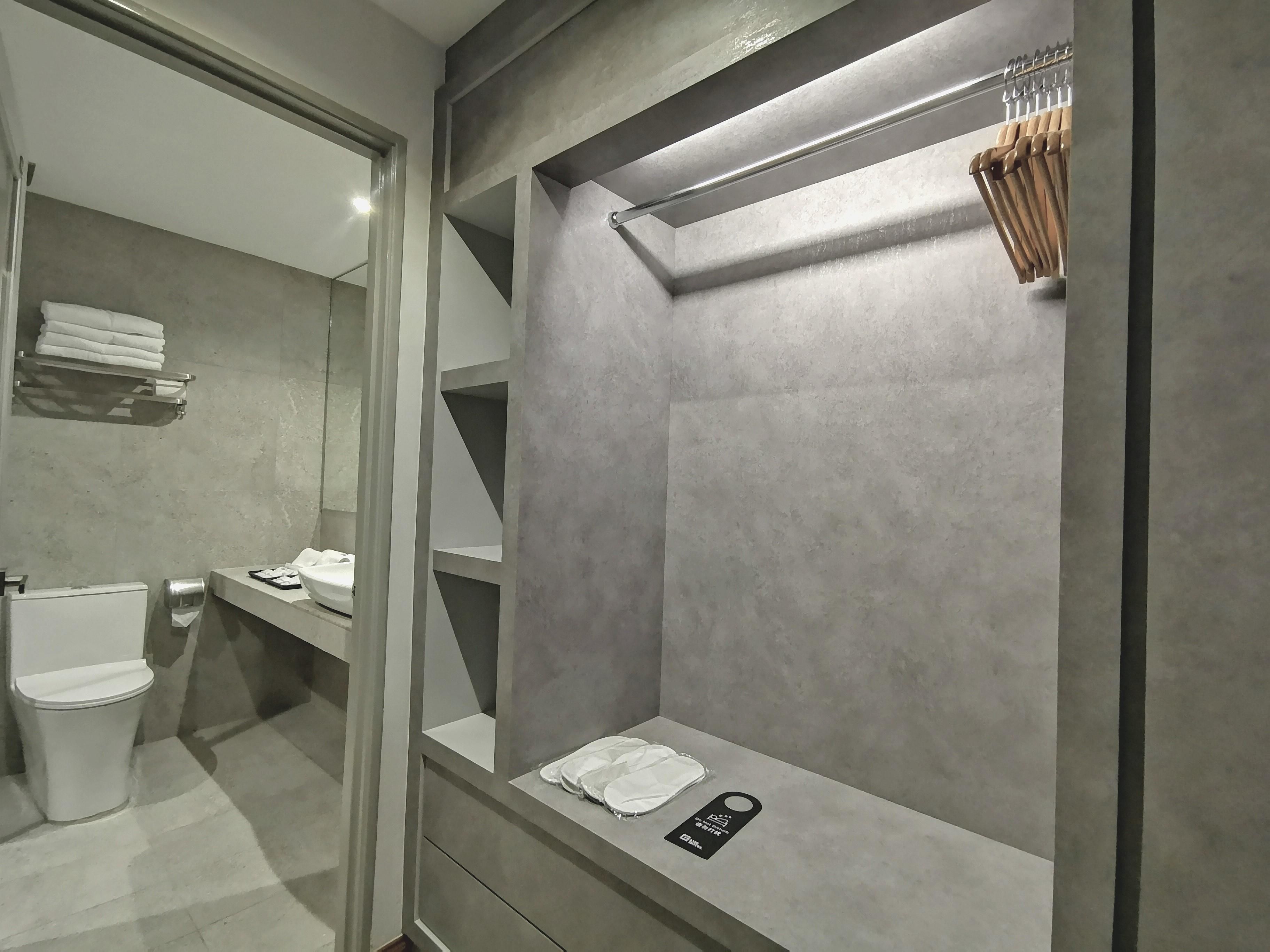 Uma casa de banho moderna com cabine de duche em vidro, sanita, porta-toalhas e um armário com artigos de higiene pessoal.