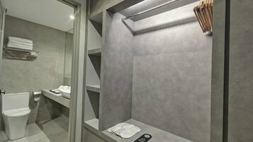 Uma casa de banho moderna com cabine de duche em vidro, sanita, porta-toalhas e um armário com artigos de higiene pessoal.