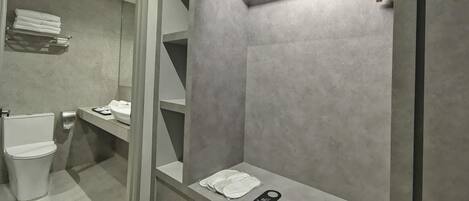 Uma casa de banho moderna com cabine de duche em vidro, sanita, porta-toalhas e um armário com artigos de higiene pessoal.
